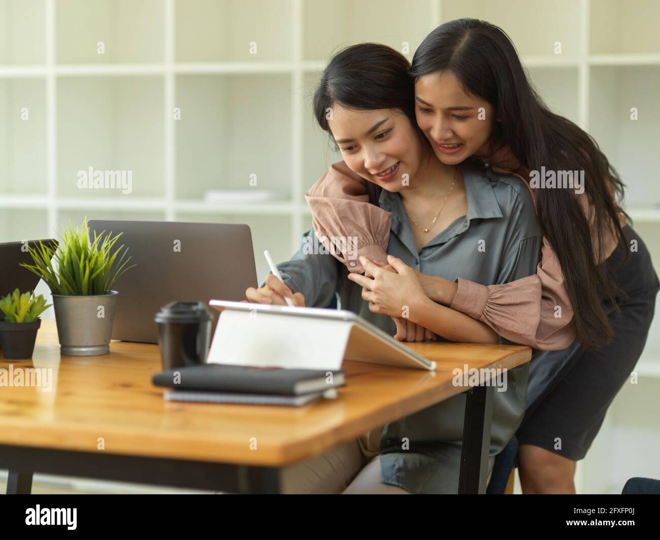 Portraits of lovely couple hugging while working on office desk in home ...