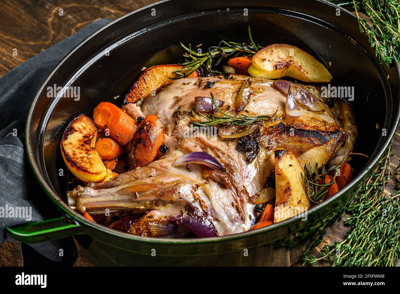 Baked whole goat shoulder leg in a baking dish. Wooden background. Top ...