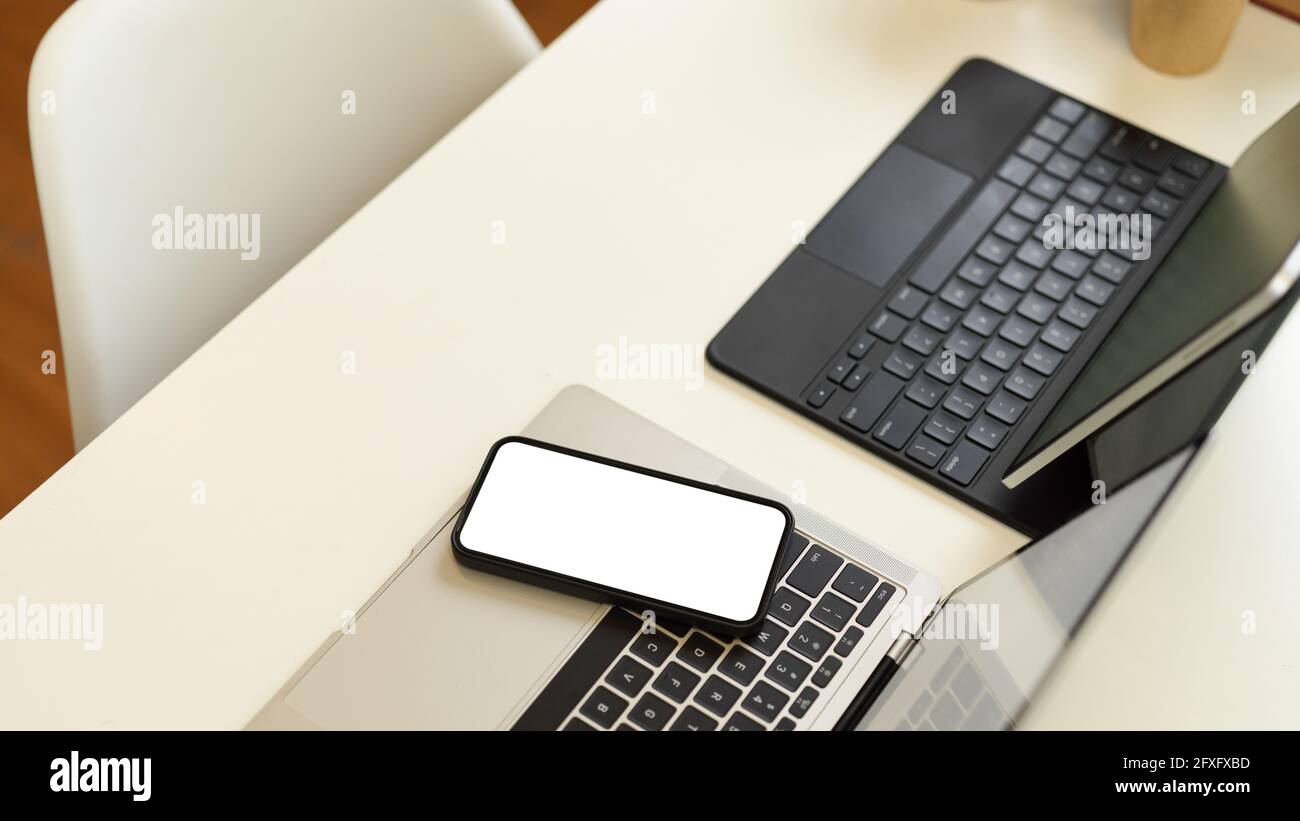 Top view of portable workspace with two laptops and smartphone on white ...