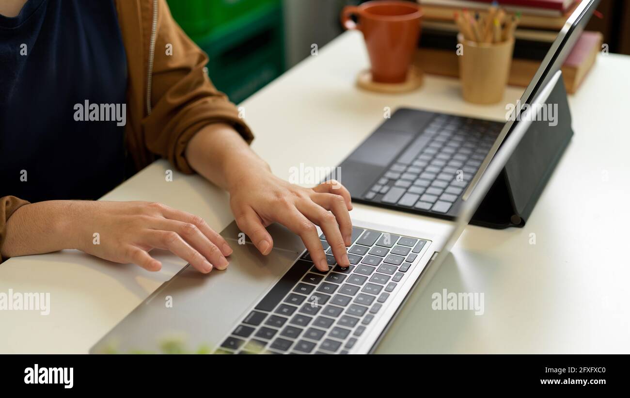 Cropped shot of female hand typing on laptop keyboard on office desk ...