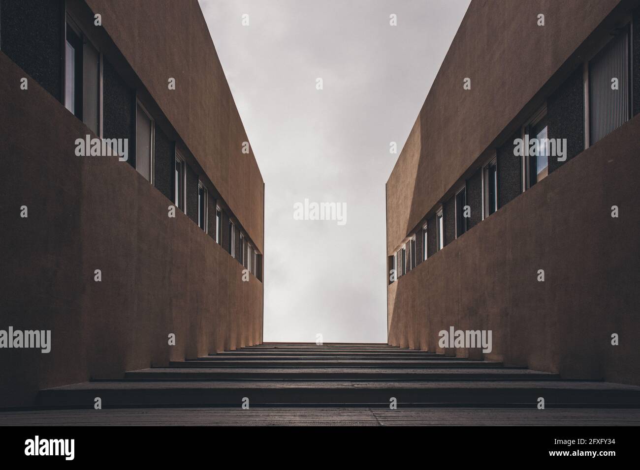 Low angle shot of a tall industrial building with a small intersection ...