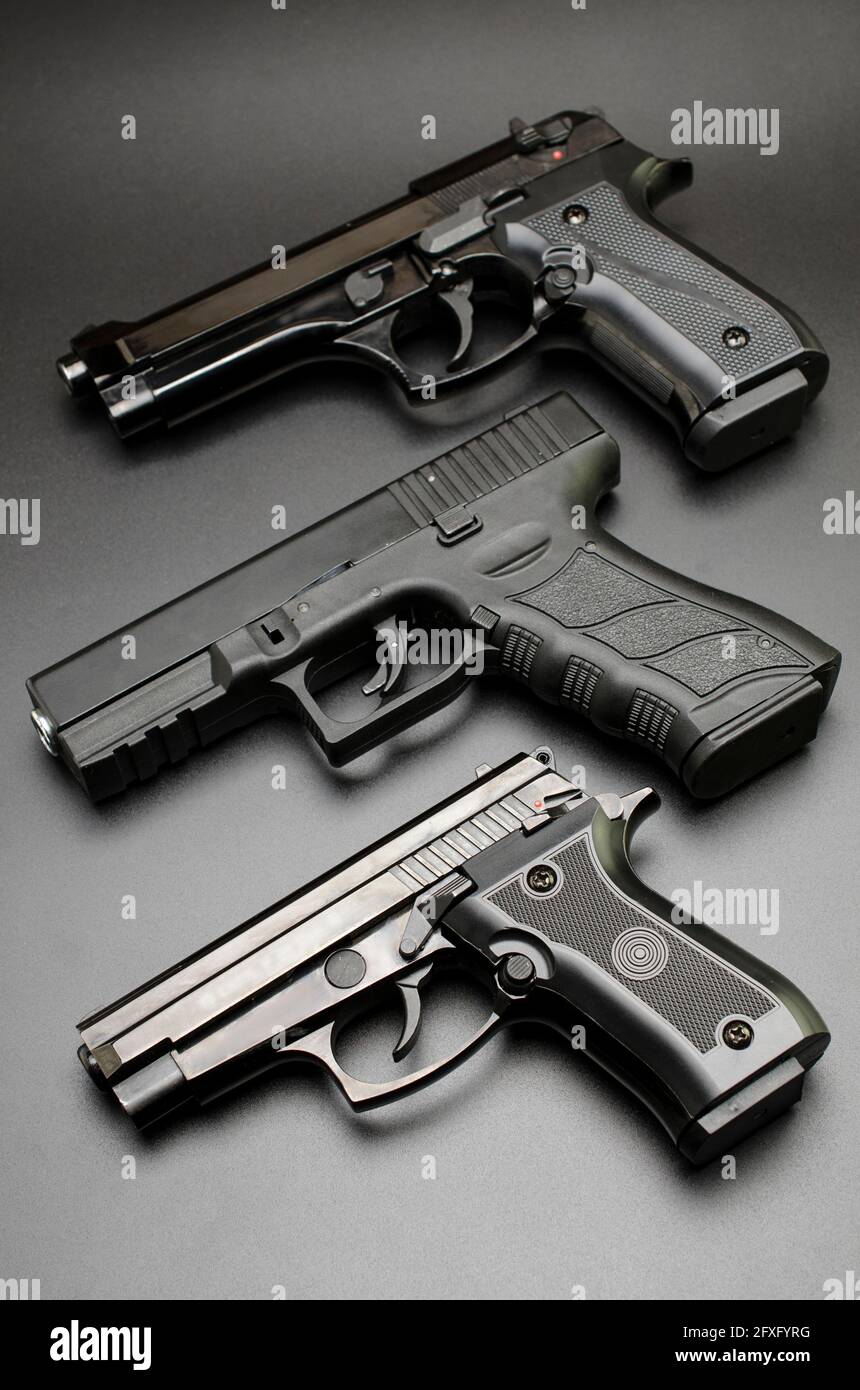 three black pistols on a black background Stock Photo - Alamy