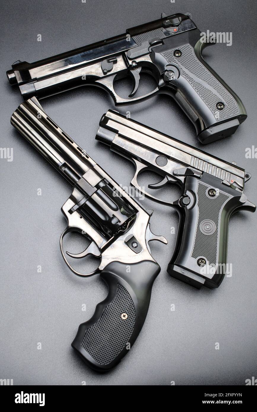 three shiny black pistols on a black background Stock Photo - Alamy