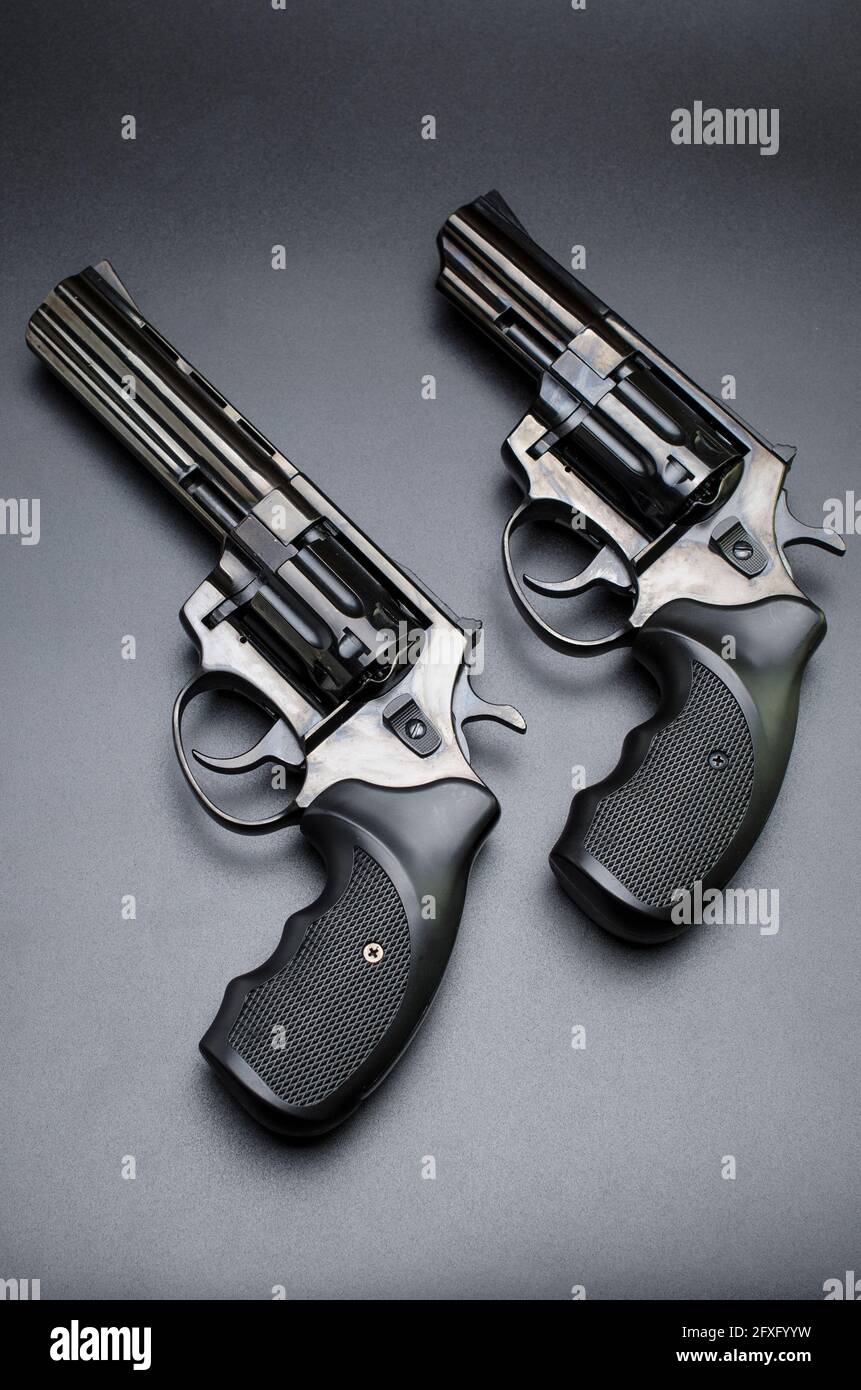 two shiny black revolvers on a black background Stock Photo - Alamy