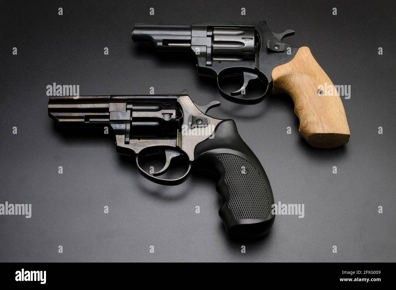 two shiny black revolvers on a black background Stock Photo - Alamy
