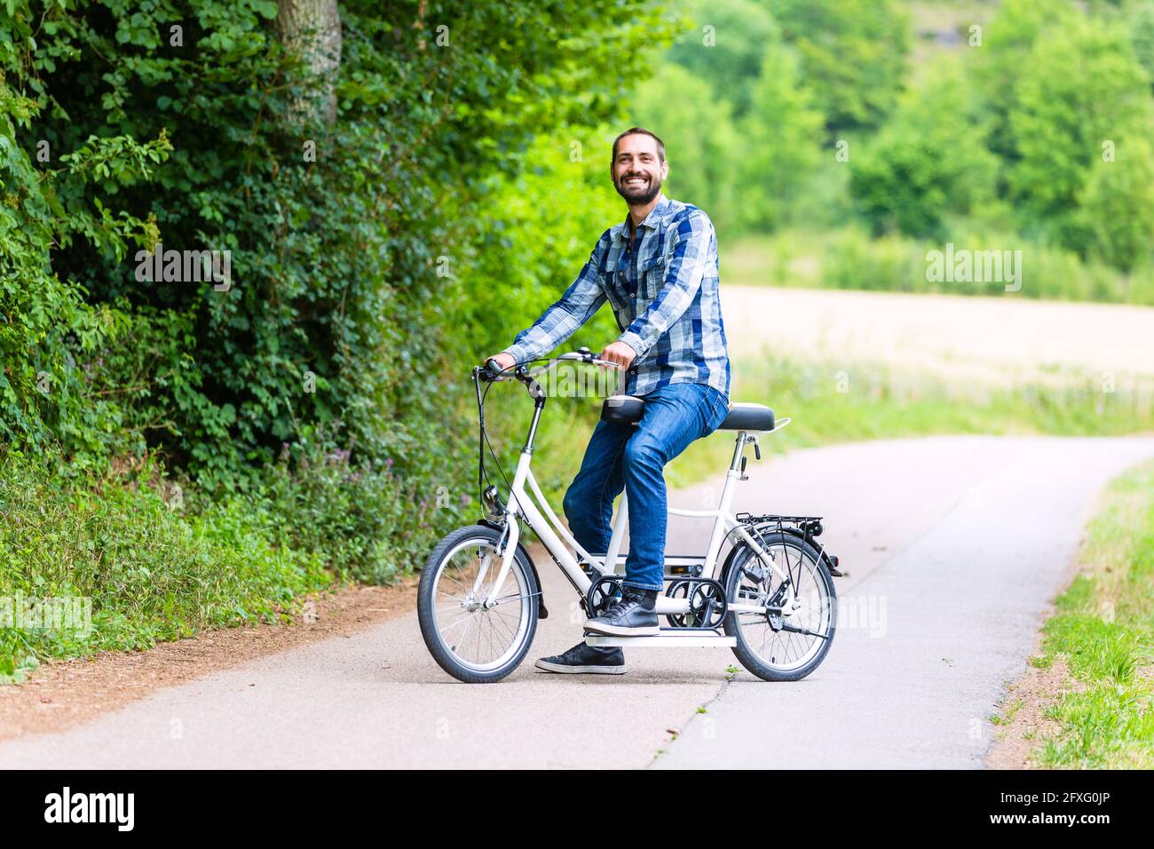 Man riding tandem bike on country lane Stock Photo - Alamy