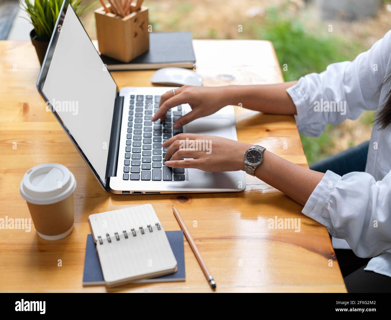 Side view of young businesswoman typing on laptop computer in modern ...