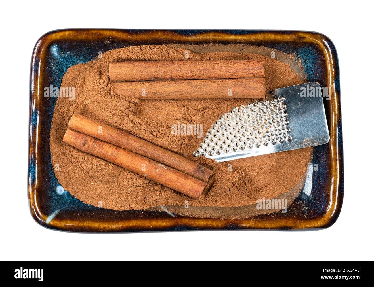top view of cassia bark, grater and cinnamon powder in ceramic bowl ...