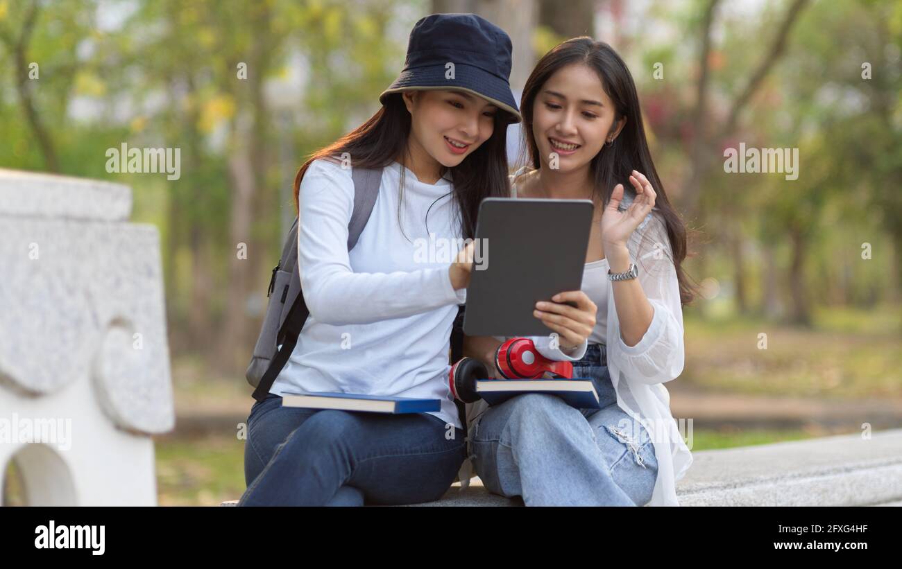 Portraits of two female university students outdoor study with digital ...
