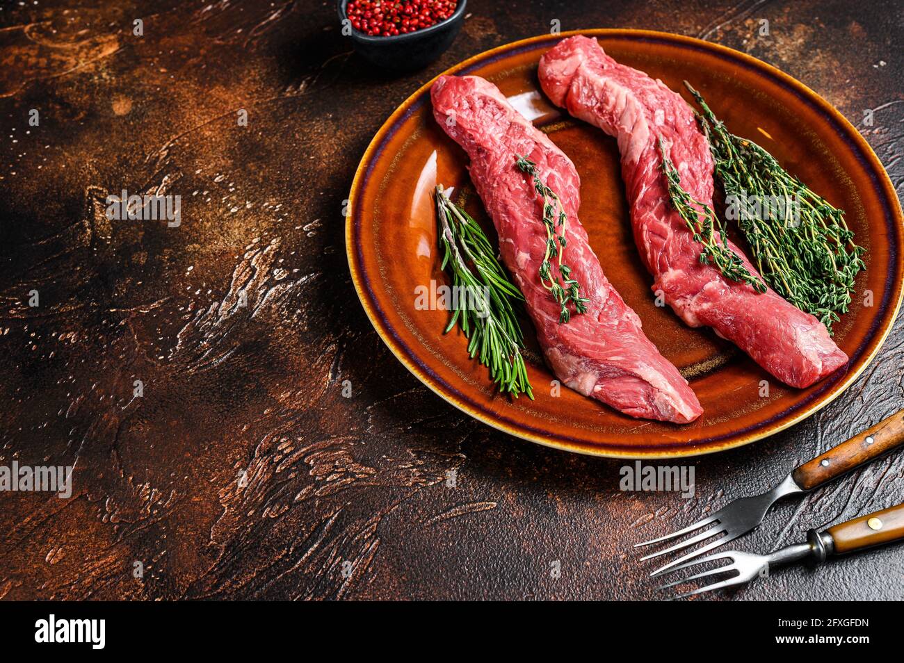 Raw flank beef meat steak on a plate. Dark background. Top view. Copy ...