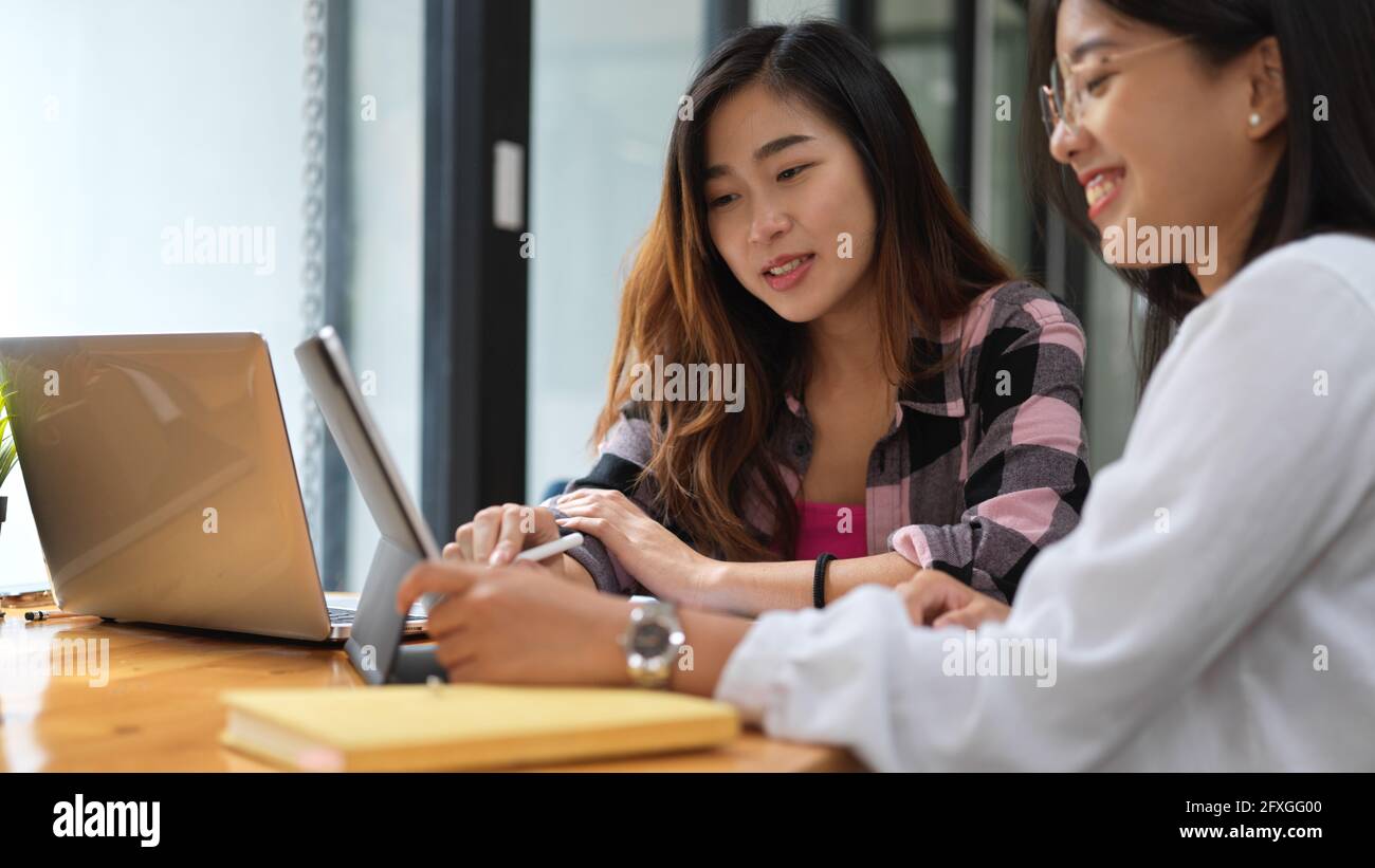Side view of two female students having funny conversation while doing ...