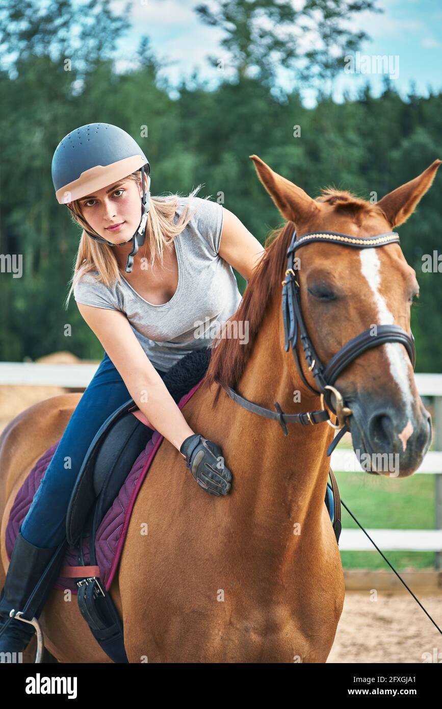girl rider in helmet stroking horse sitting astride Stock Photo - Alamy