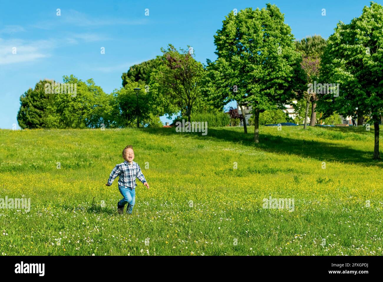 Cute little boy running across grass und smiling outdoors in a public ...