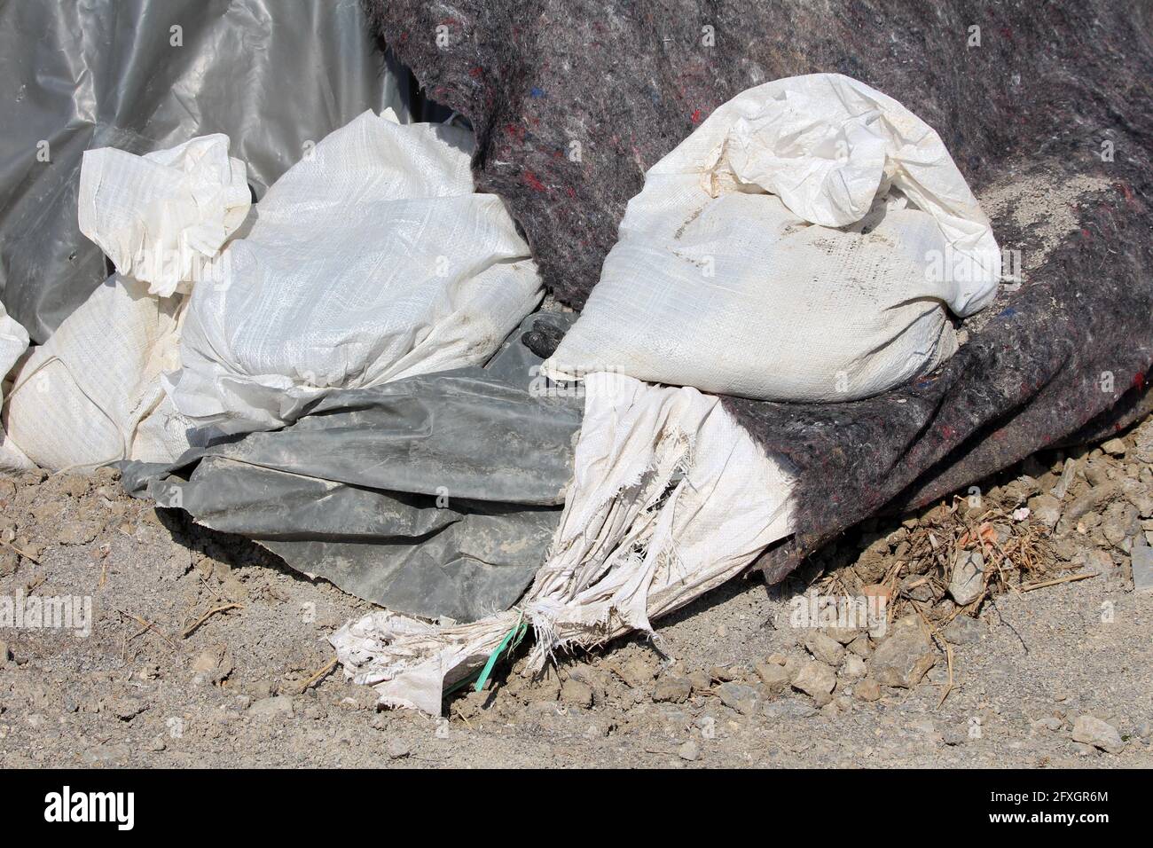 Bunch of new and old broken and ripped apart white sandbags holding ...