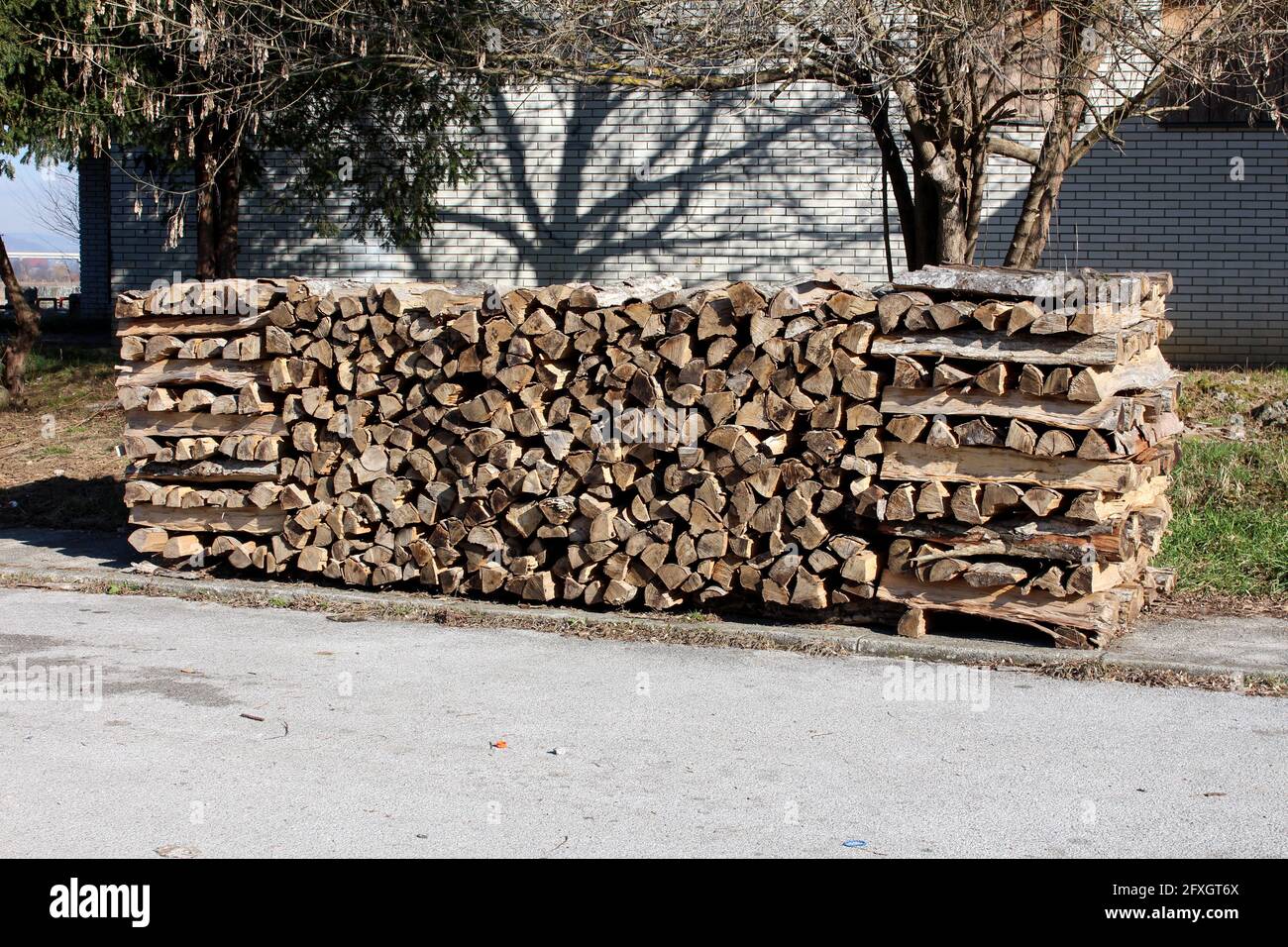 Stacked dry firewood left on sidewalk in front of suburban family house ...