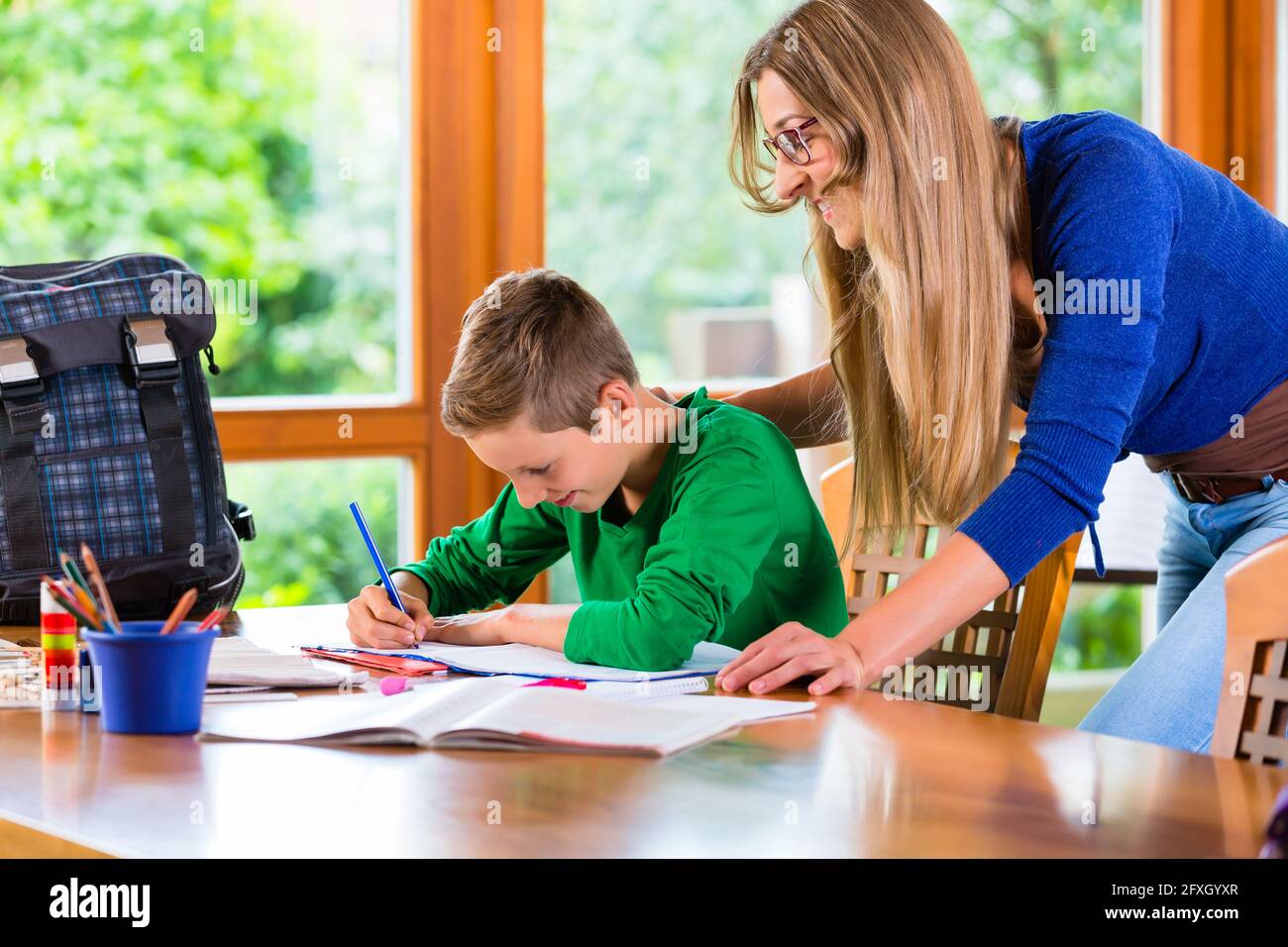 Mother helping son with school homework assignment for school at home ...