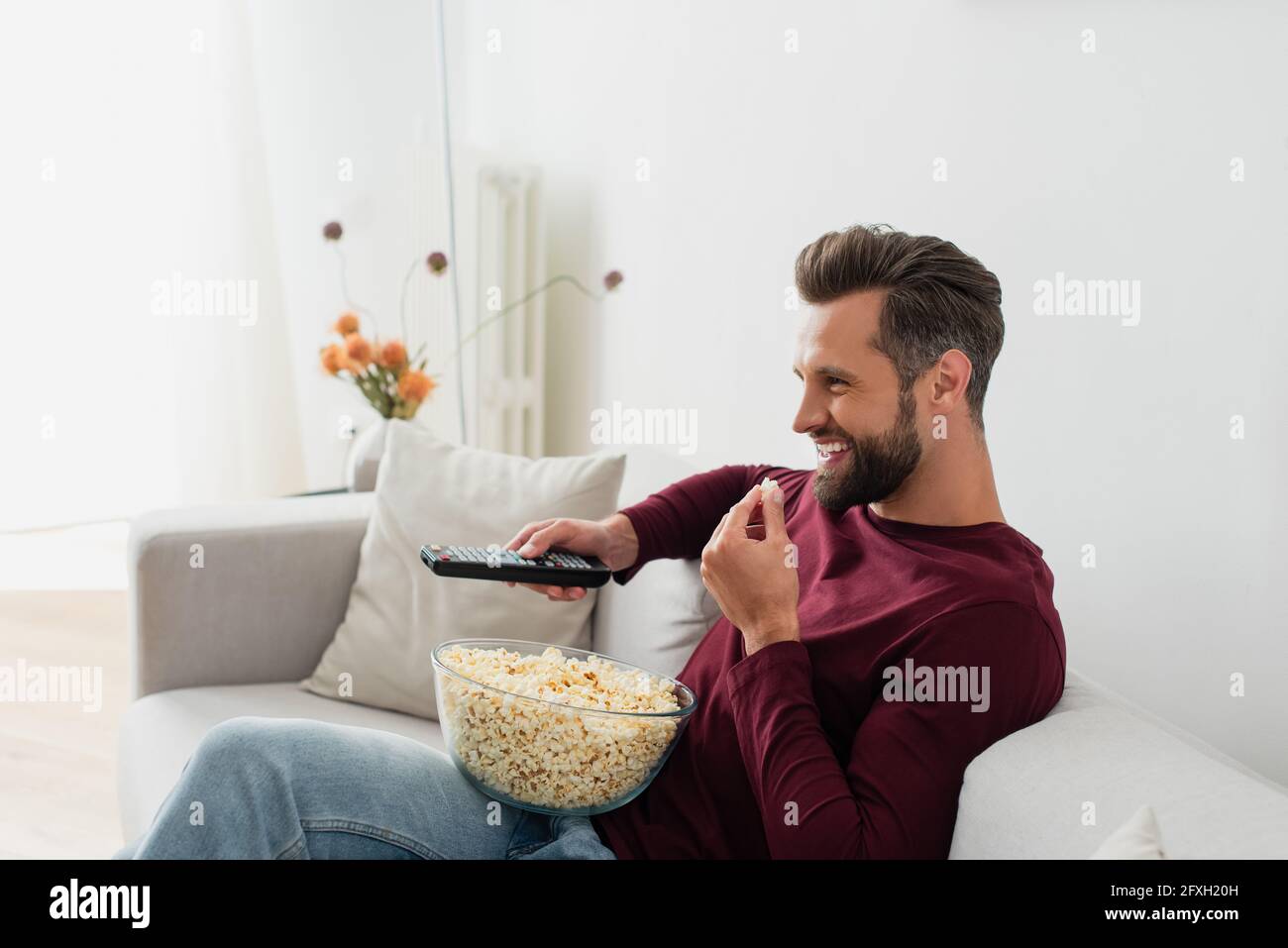 laughing man eating popcorn while watching comedy film in living room ...