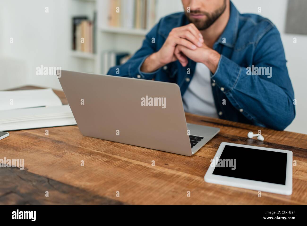 partial view of blurred teleworker working near laptop and digital ...