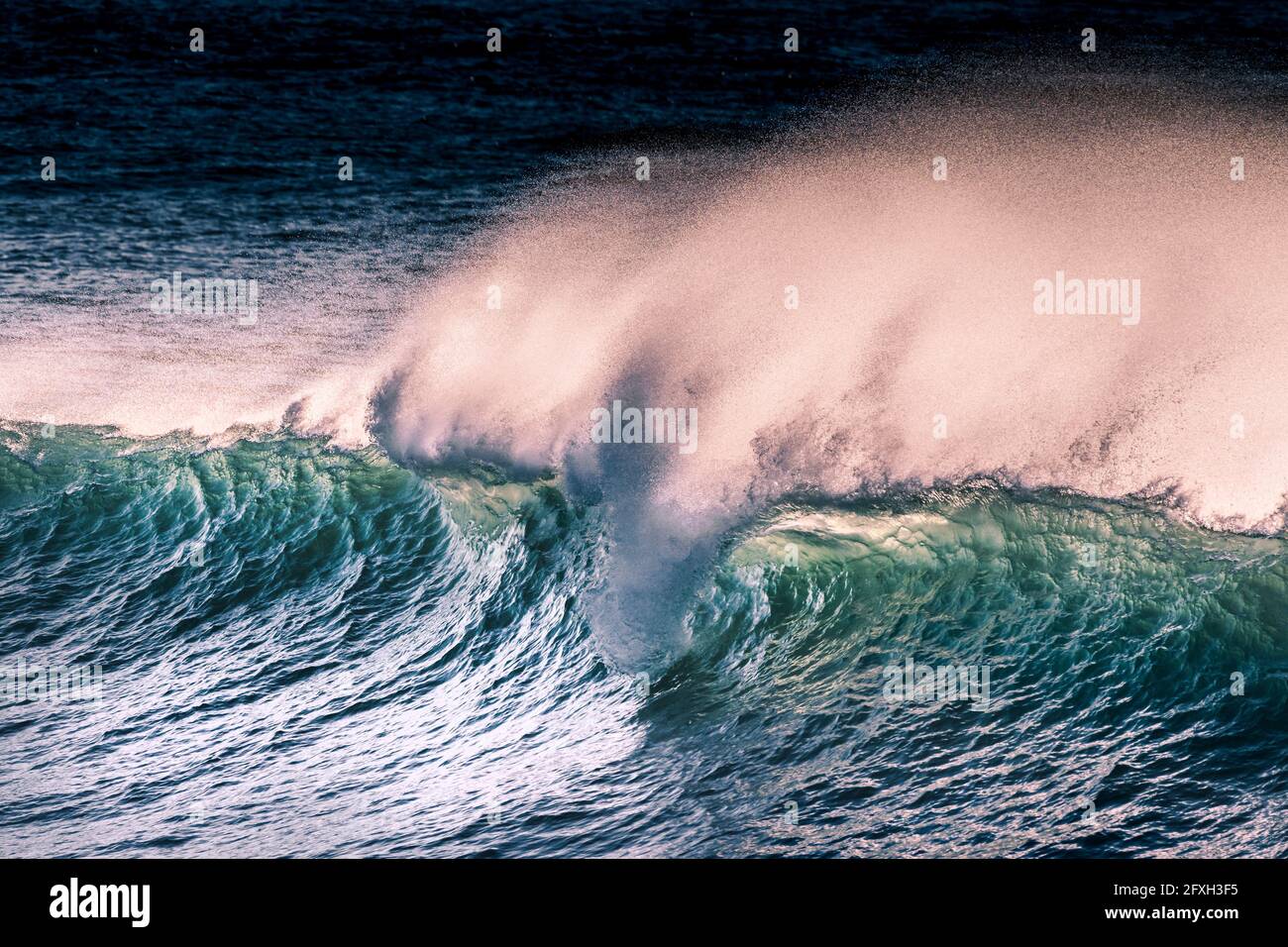 A wave breaking and spray being blown by strong offshore wind on the ...