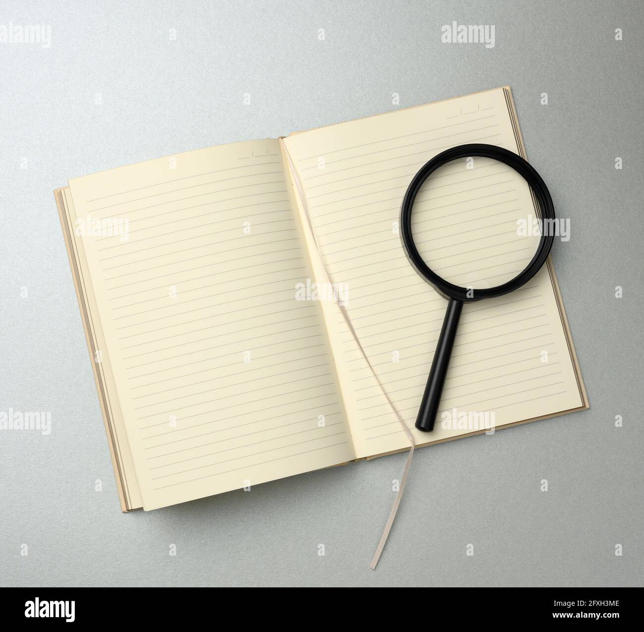 paper notebook with blank white sheets and a black magnifier on a gray ...