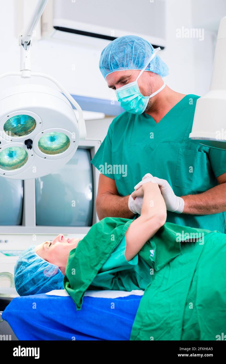 Surgeon in operating room holding hand of patient consoling her and ...