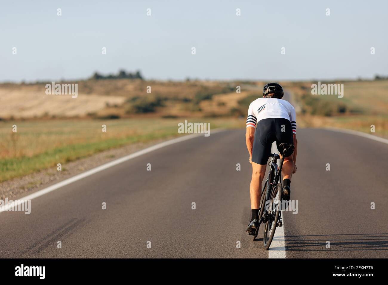 Back view of athlete in helmet cycling outdoors Stock Photo - Alamy