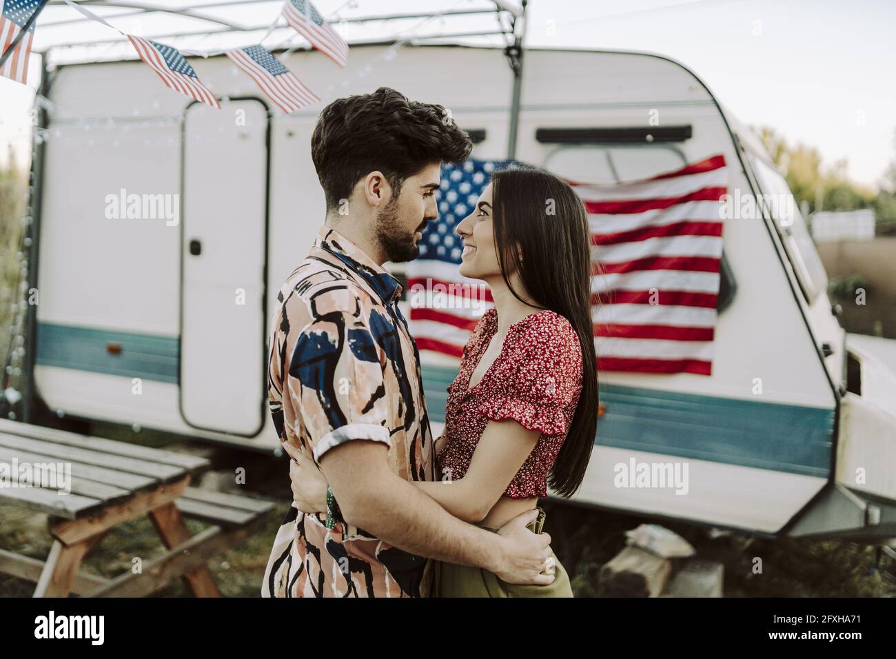 A beautiful Spanish couple hugging on background of the US flag - US ...