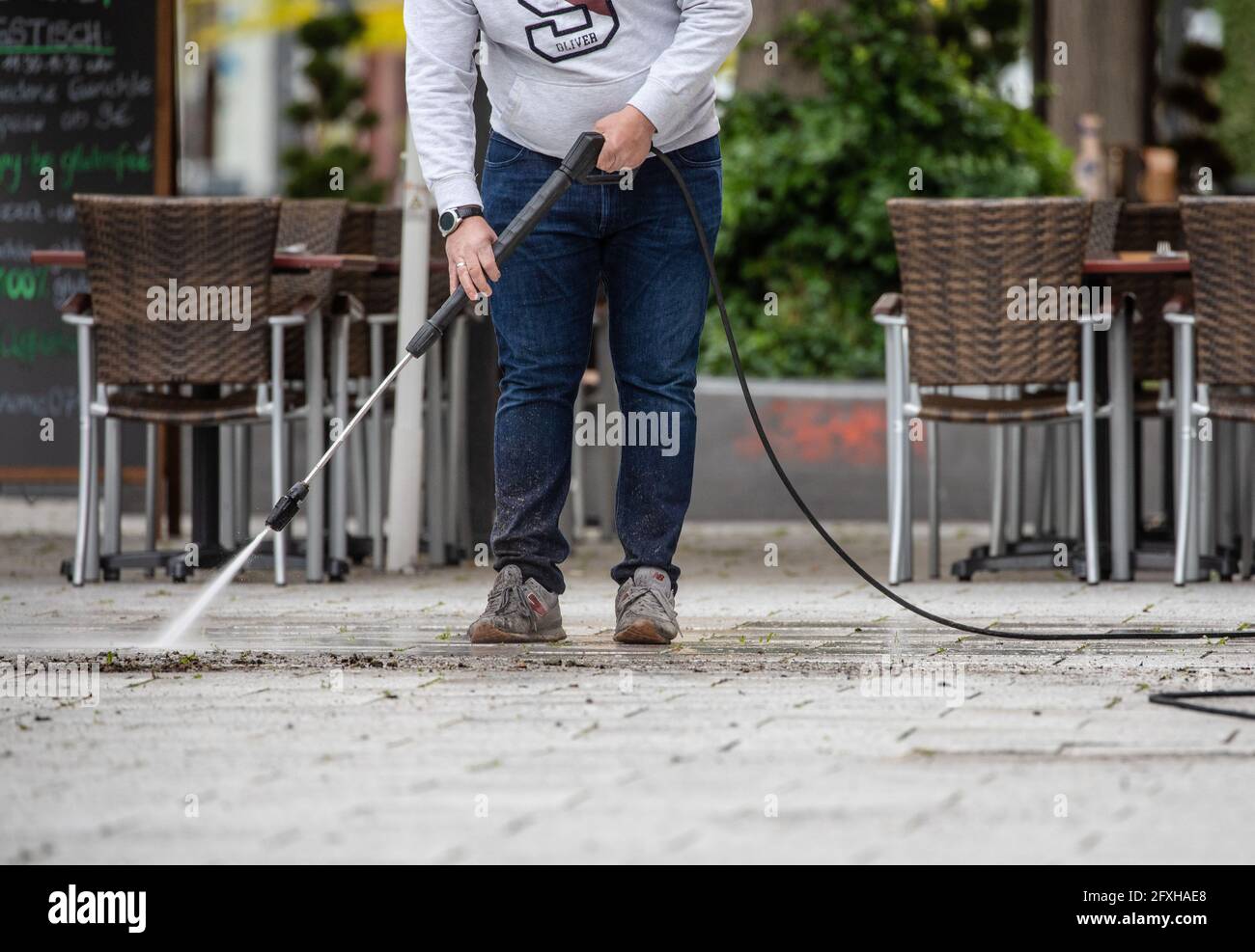 Stuttgart, Germany. 27th May, 2021. A man cleans the patio of a ...