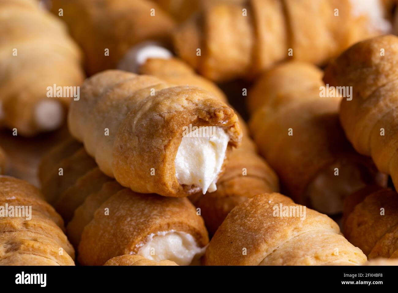 Lots of sweet home made pastry tubes with cream. Photo taken under soft ...