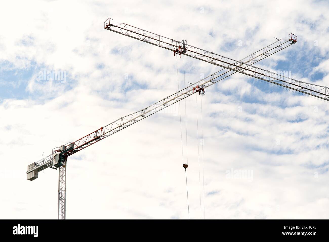 Two tower cranes with crossed booms at a construction site against a ...