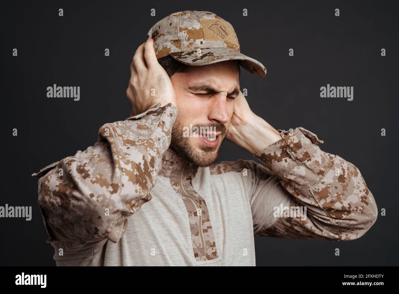 Unhappy masculine military man with headache rubbing his temples ...