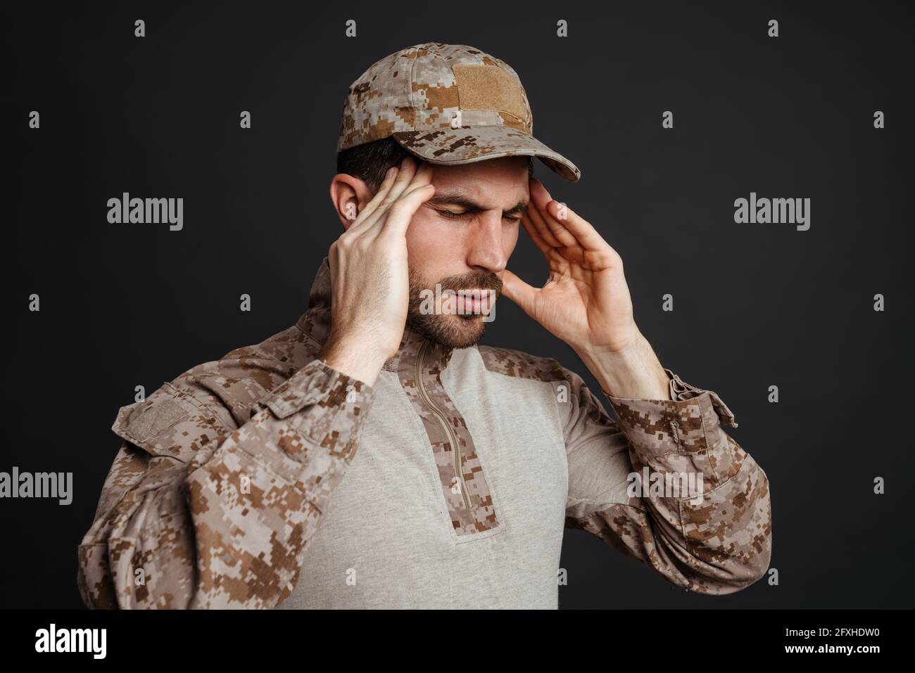 Unhappy masculine military man with headache rubbing his temples ...