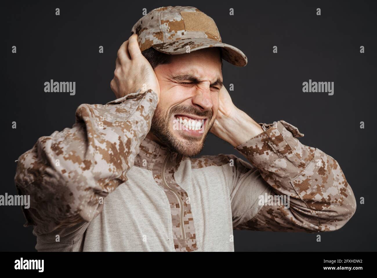 Unhappy masculine military man with headache rubbing his temples ...