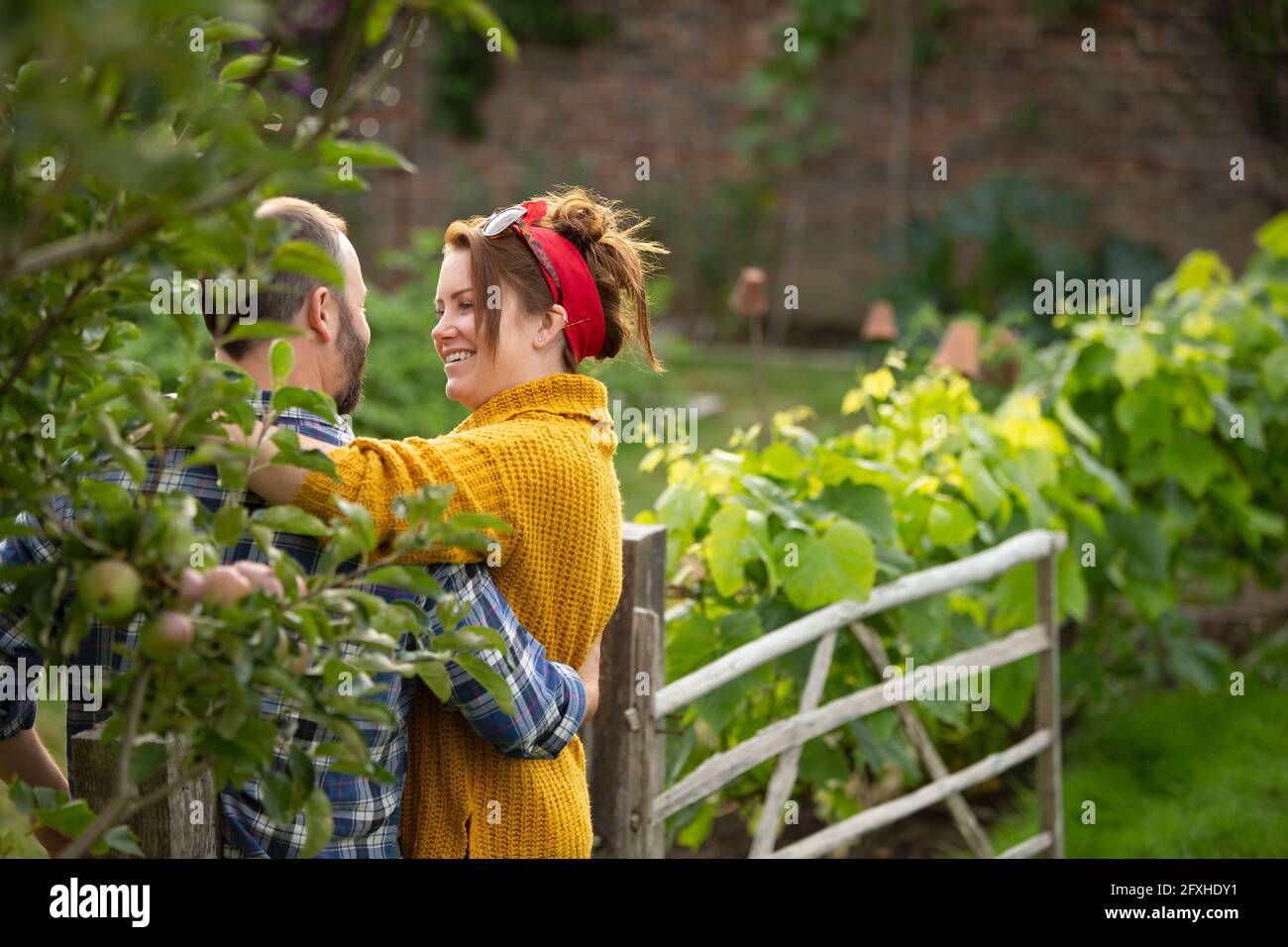 Happy couple hugging and talking in garden Stock Photo - Alamy