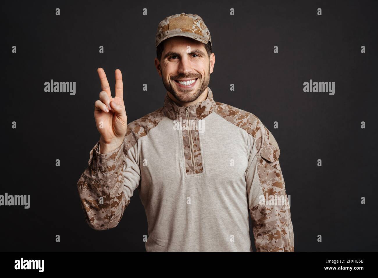 Happy masculine military man smiling and gesturing peace sign isolated ...