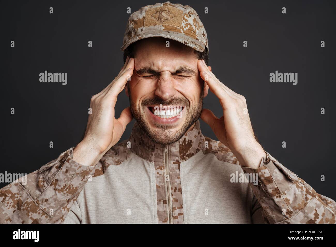 Unhappy masculine military man with headache rubbing his temples ...