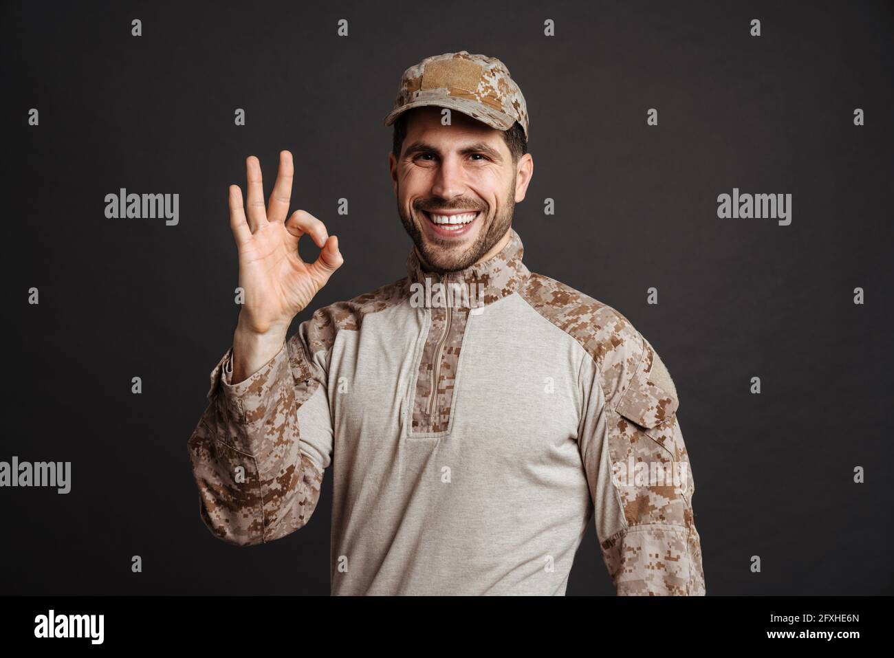 Happy masculine military man smiling and showing ok sign isolated over ...