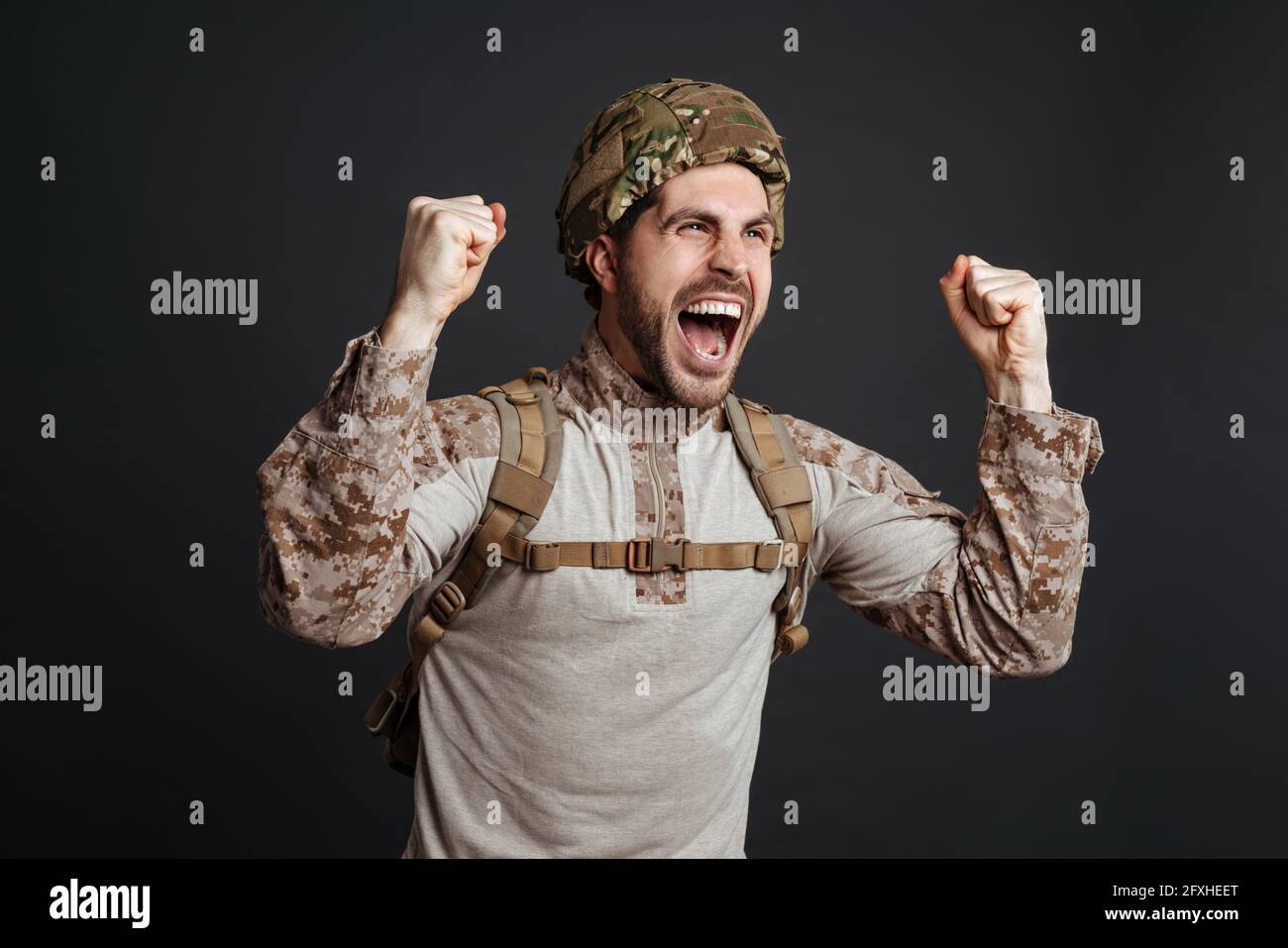 Excited military man in helmet screaming and making winner gesture ...