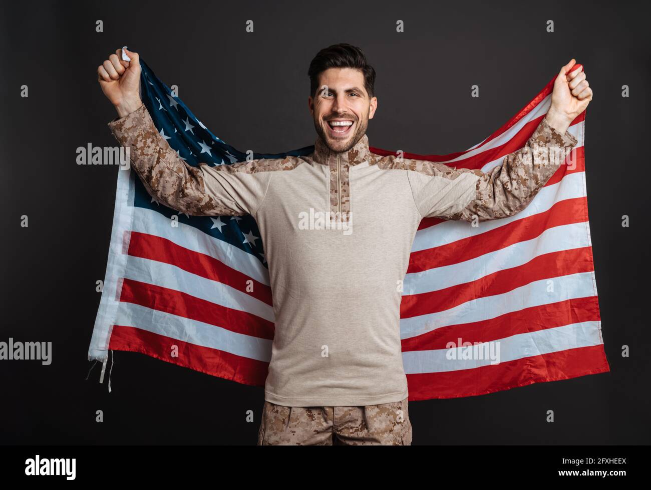 Happy masculine military man smiling while posing with american flag ...