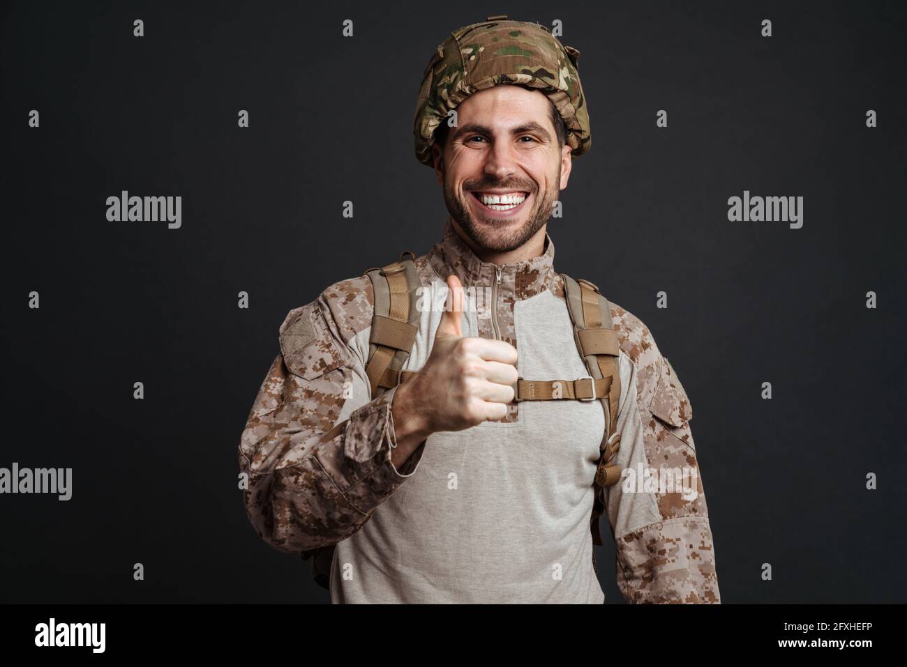Happy military man wearing helmet smiling and showing thumb up isolated ...