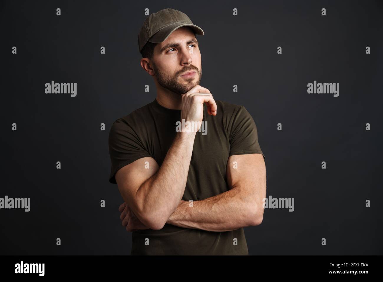 Focused masculine military man posing and looking aside isolated over ...