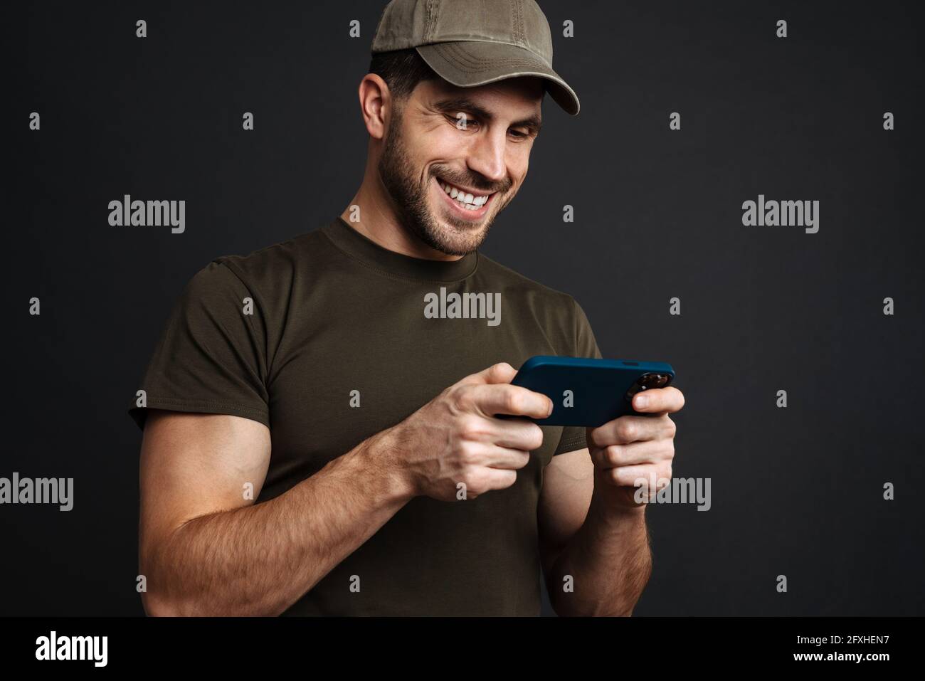 Happy masculine military man playing online game on mobile phone ...