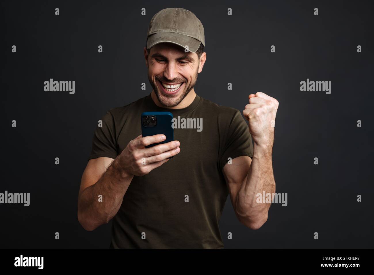 Excited military man making winner gesture while using cellphone ...