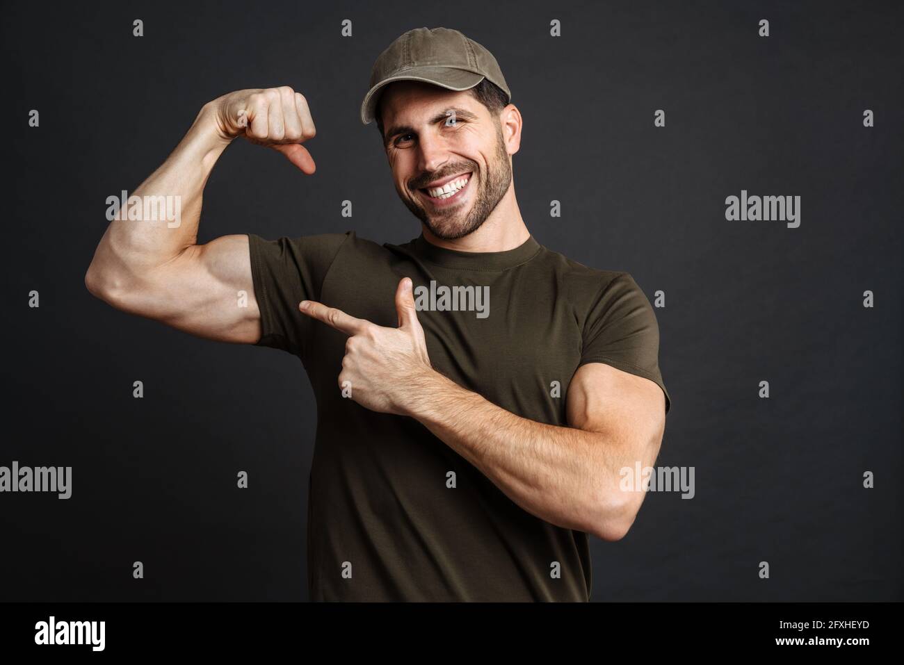 Strong healthy military man showing biceps isolated over black wall ...