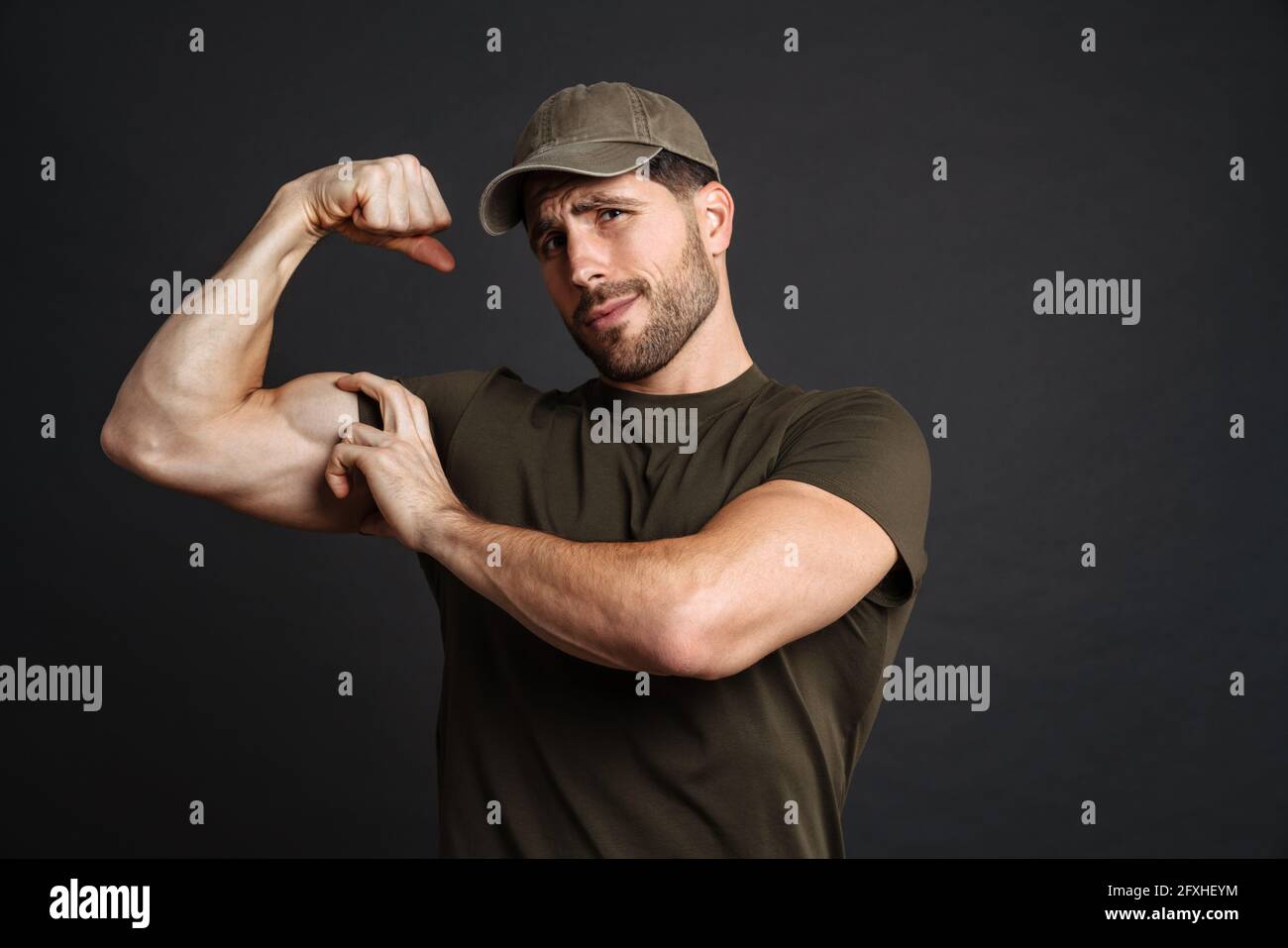 Strong healthy military man showing biceps isolated over black wall ...