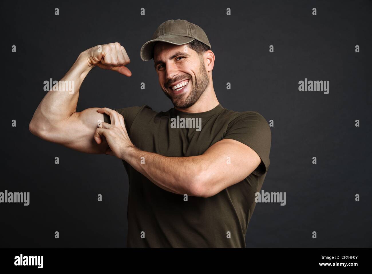 Strong healthy military man showing biceps isolated over black wall ...