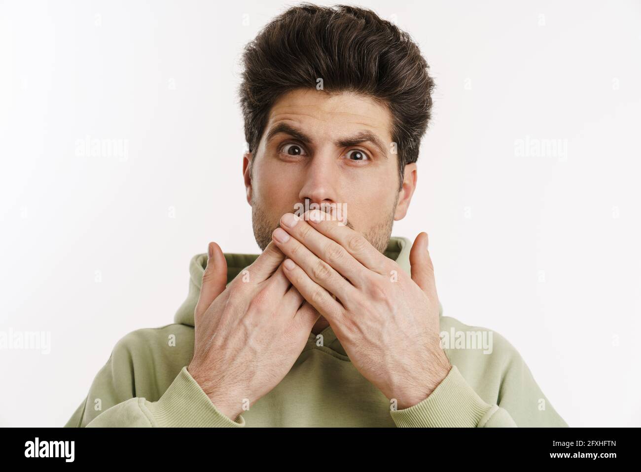 Shocked handsome man in sportswear covering his mouth isolated over ...