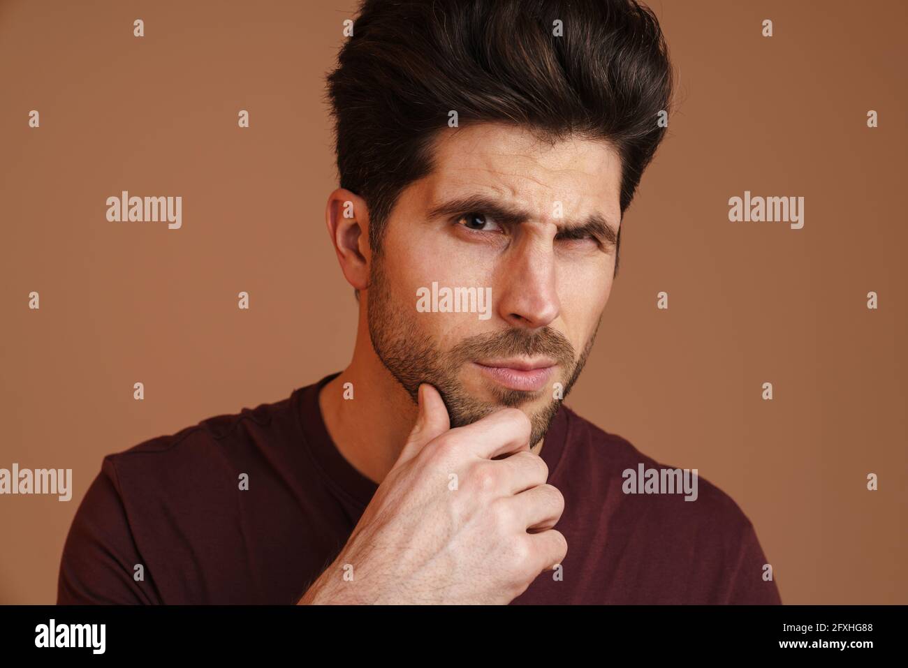 Brooding handsome man posing and looking at camera isolated over beige ...