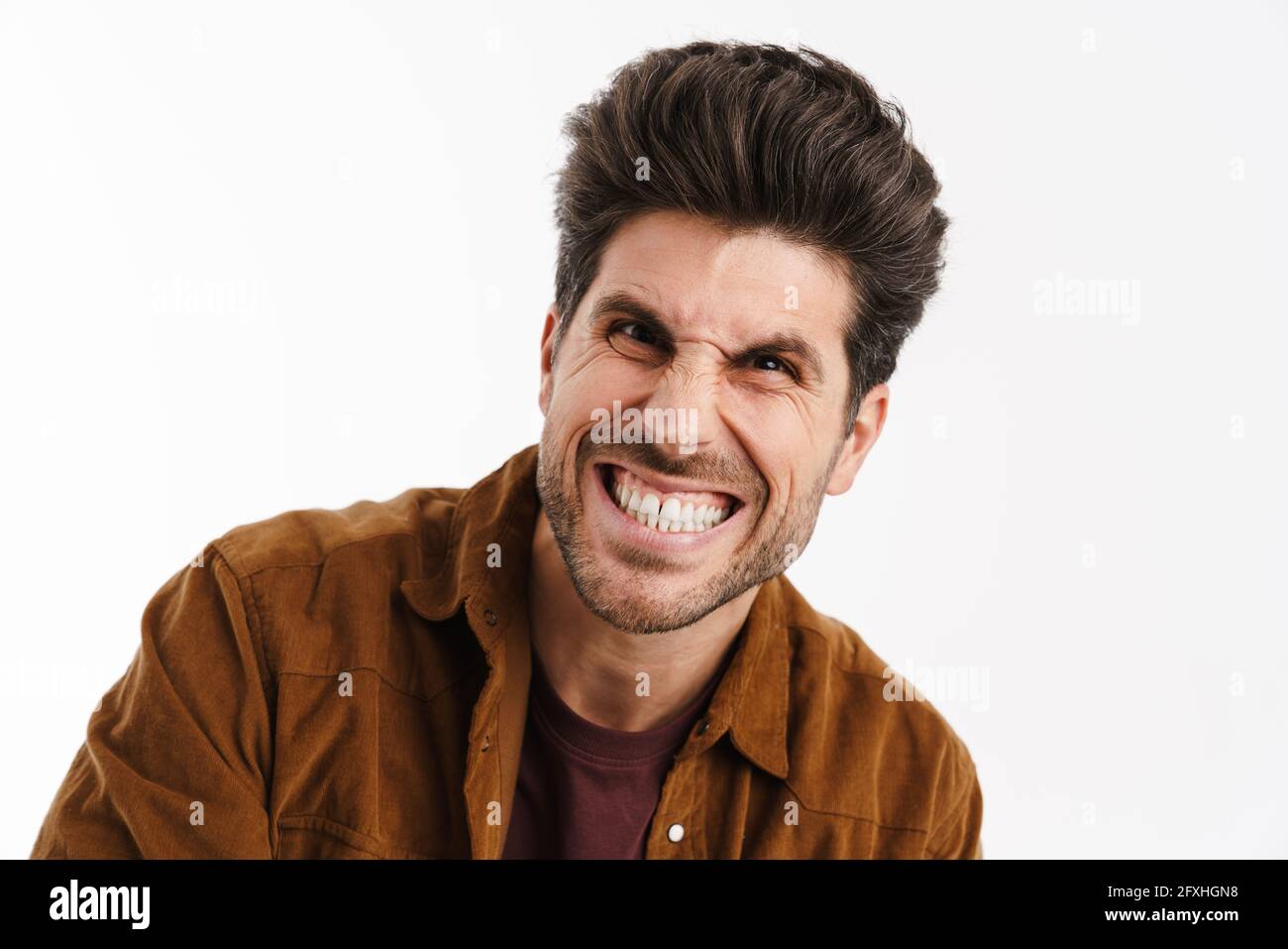 Angry handsome young man grimacing and looking at camera isolated over ...