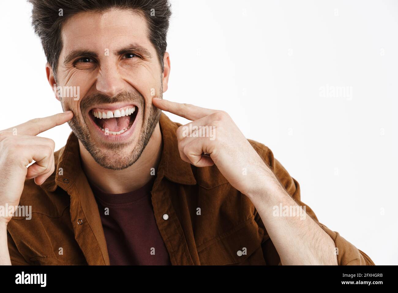 Happy handsome man smiling and pointing fingers at his cheeks isolated ...